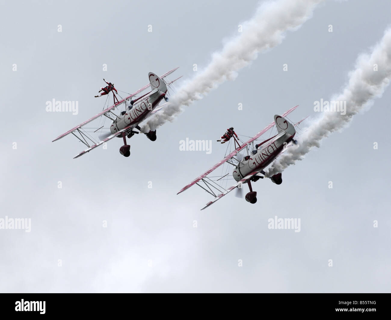 Stunt flying bi-planes with a female wing walker standing on the top ...