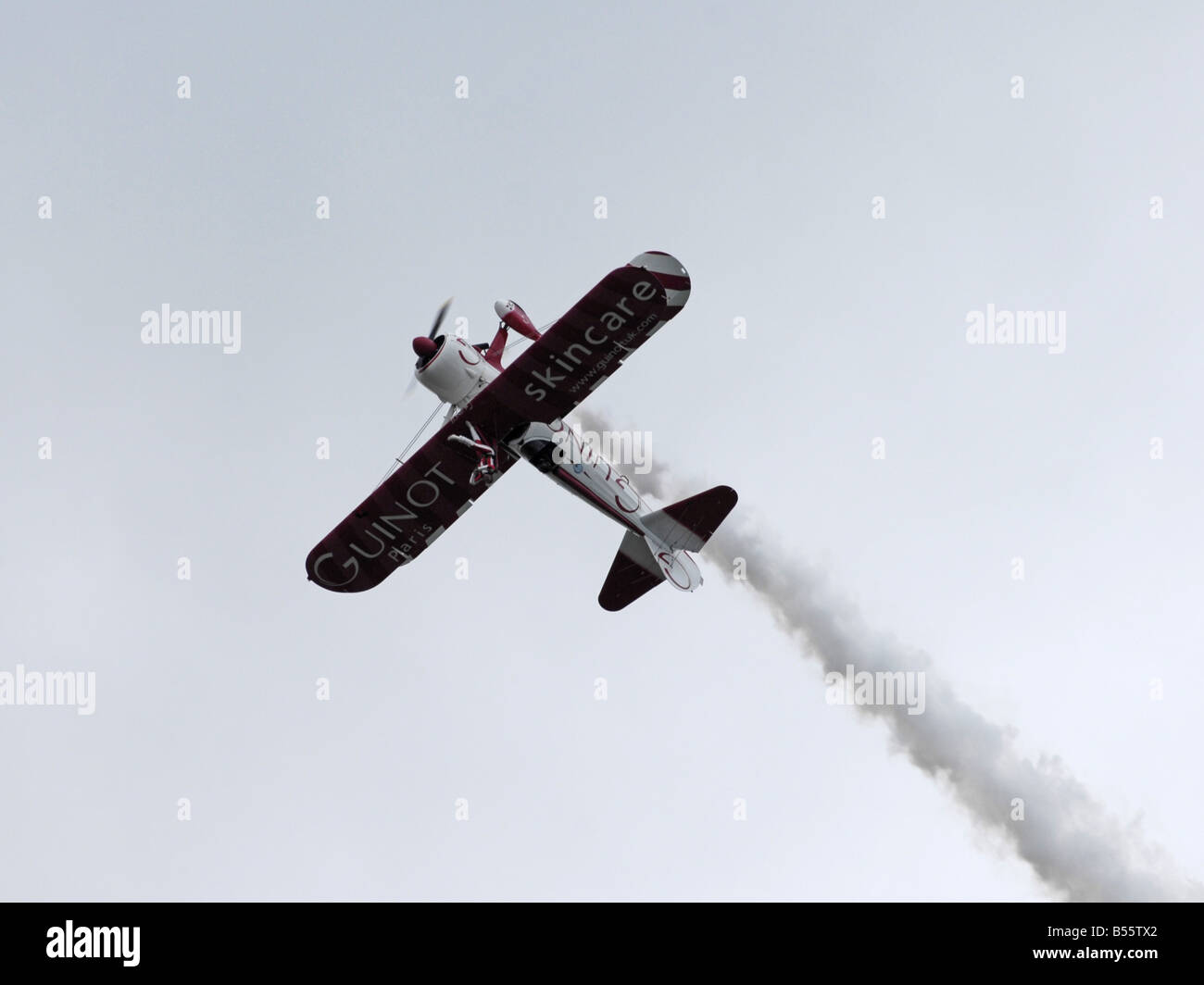 Stunt flying bi-plane with a female wing walker standing on the top ...