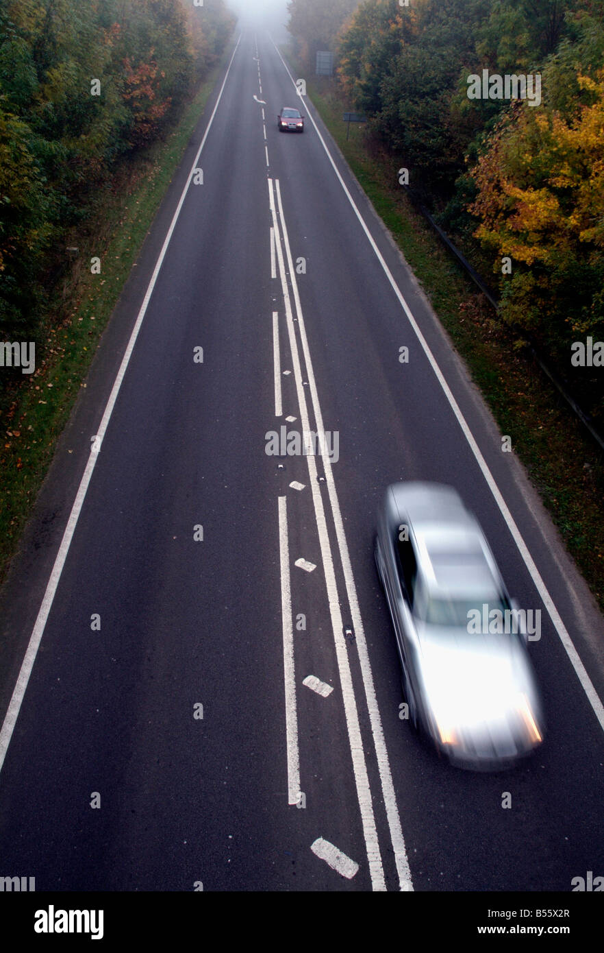 two cars following each other through woodland on straight road in ...