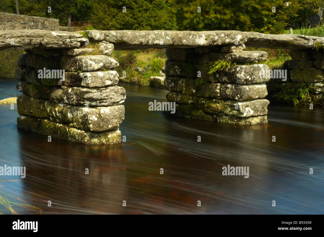 The River Dart flowing under a stone clapper bridge on Dartmoor Devon ...