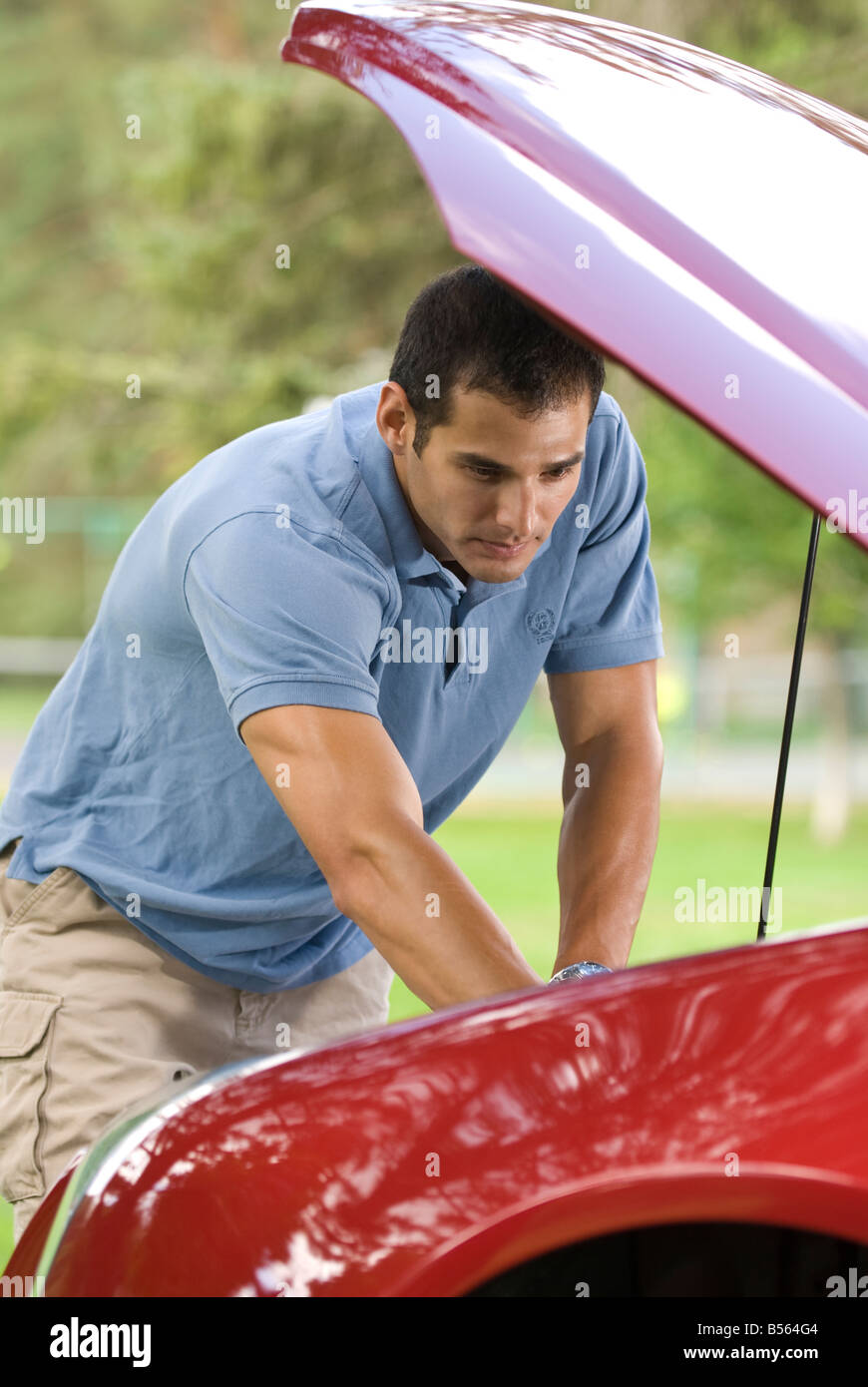 Man reaching into car engine trying to fix it Stock Photo - Alamy