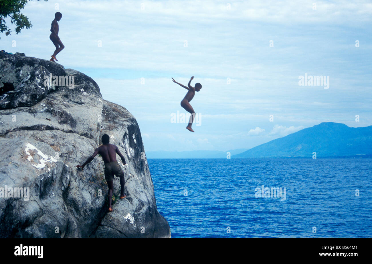 boys jumping from a cliff on an island near Kande Beach, Lake Malawi ...
