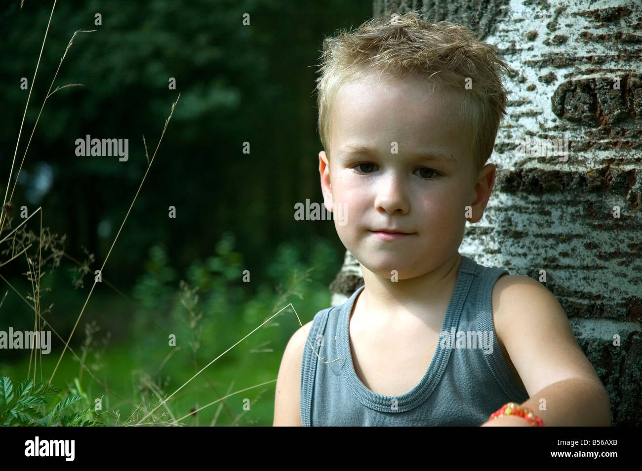 Six year old thinking against a tree Stock Photo - Alamy