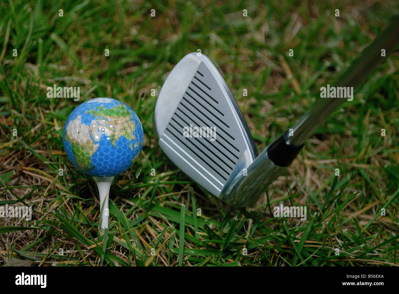 A golf ball depicting the earth sits on a golf tee with a golf club ...