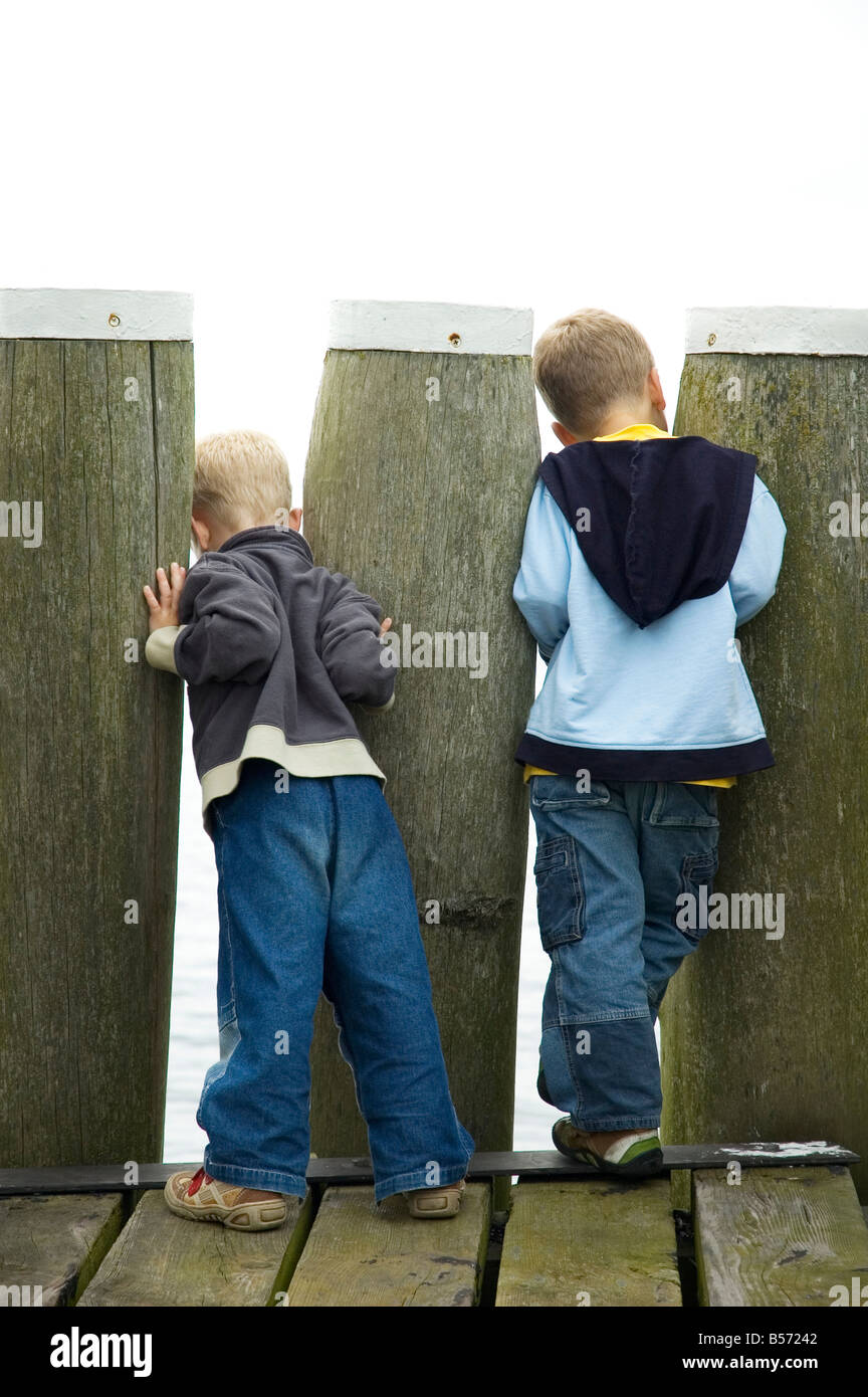 Two boys looking though a couple of poles to see what s beyond On white ...