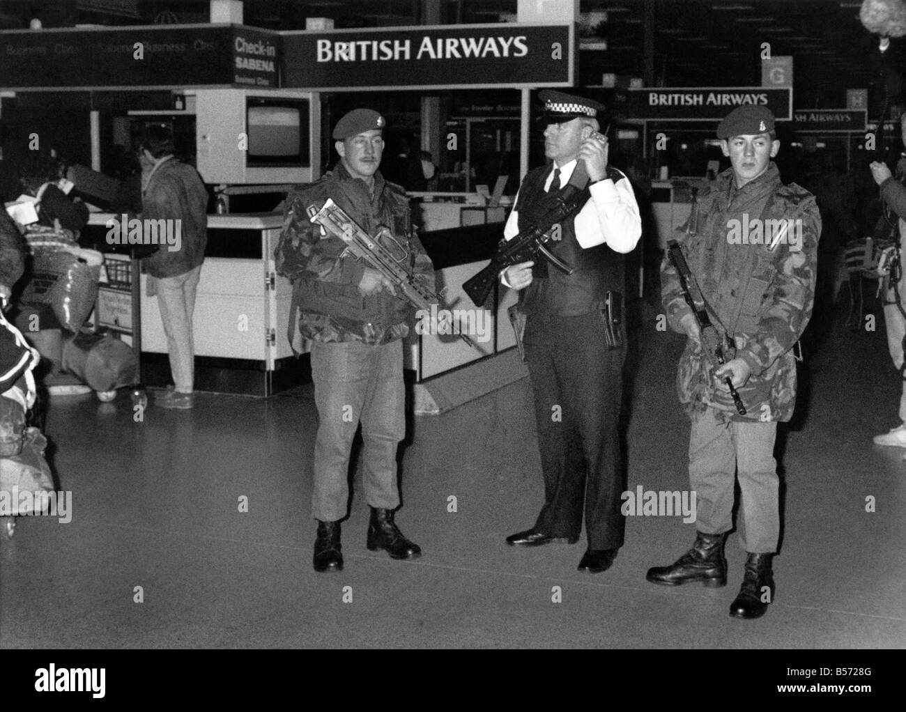 Soldiers with machine guns tand alongside an armed police officer as ...