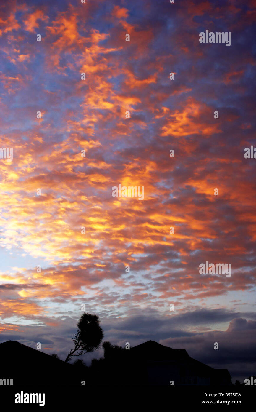 The setting sun colors the clouds of a summer sky behind beach cottages ...