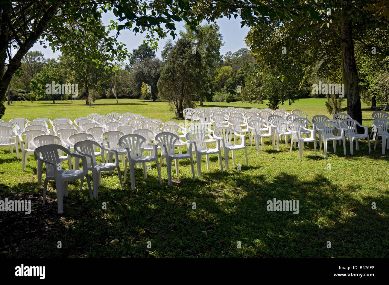 line up of white chairs in garden setting Stock Photo - Alamy