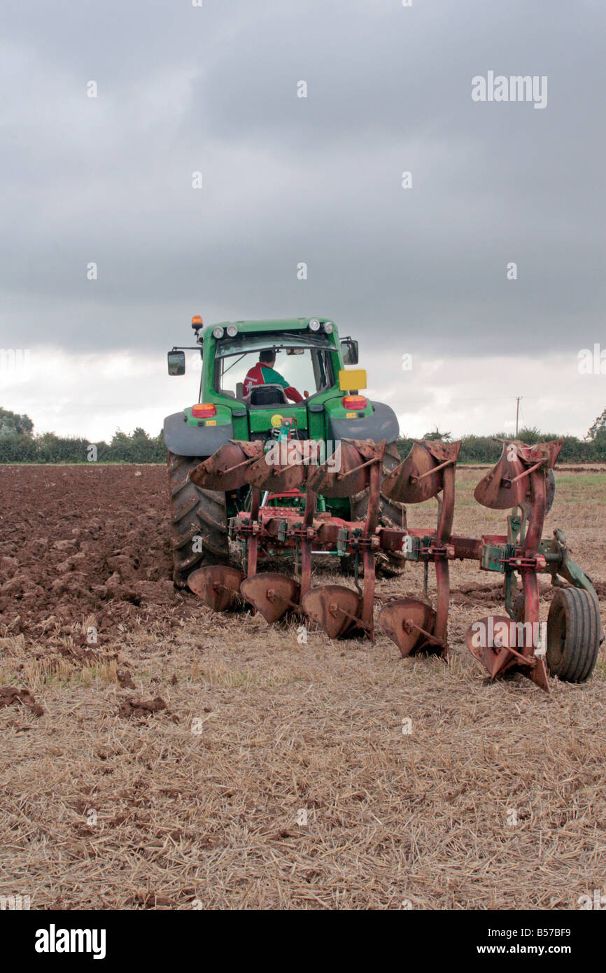 British farmer hard at work ploughing his field using a reversible ...