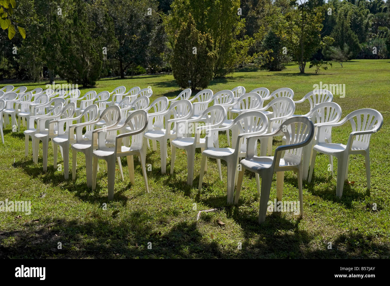 line up of white chairs in garden setting Stock Photo - Alamy