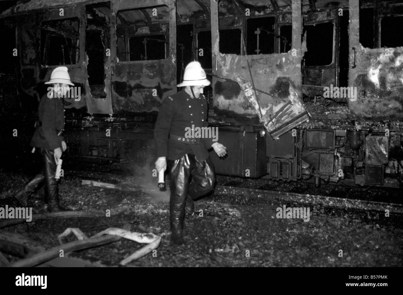 Firefighters attend to a burnt out railway carriage which was destroyed ...