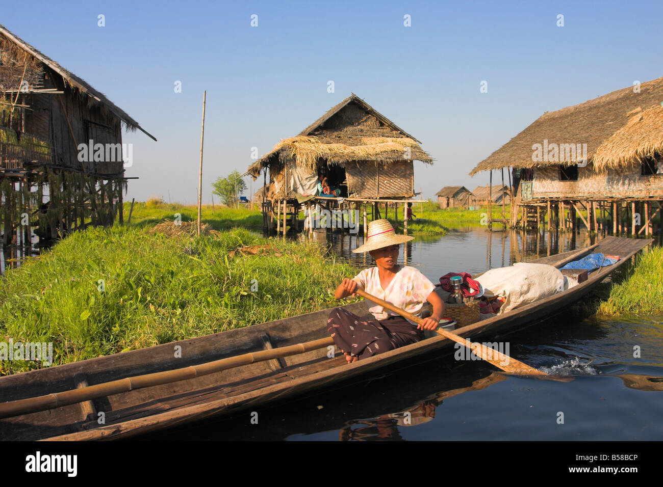 Woman in canoe paddles past floating village Inle Lake Shan State ...