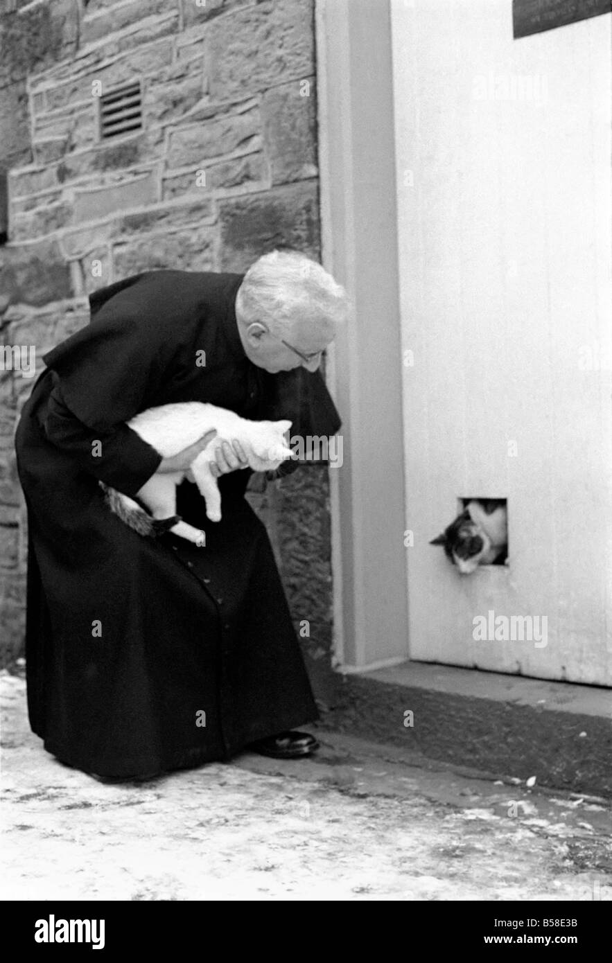 The parish priest seen here gathering up his pet cats.. February 1970 ...