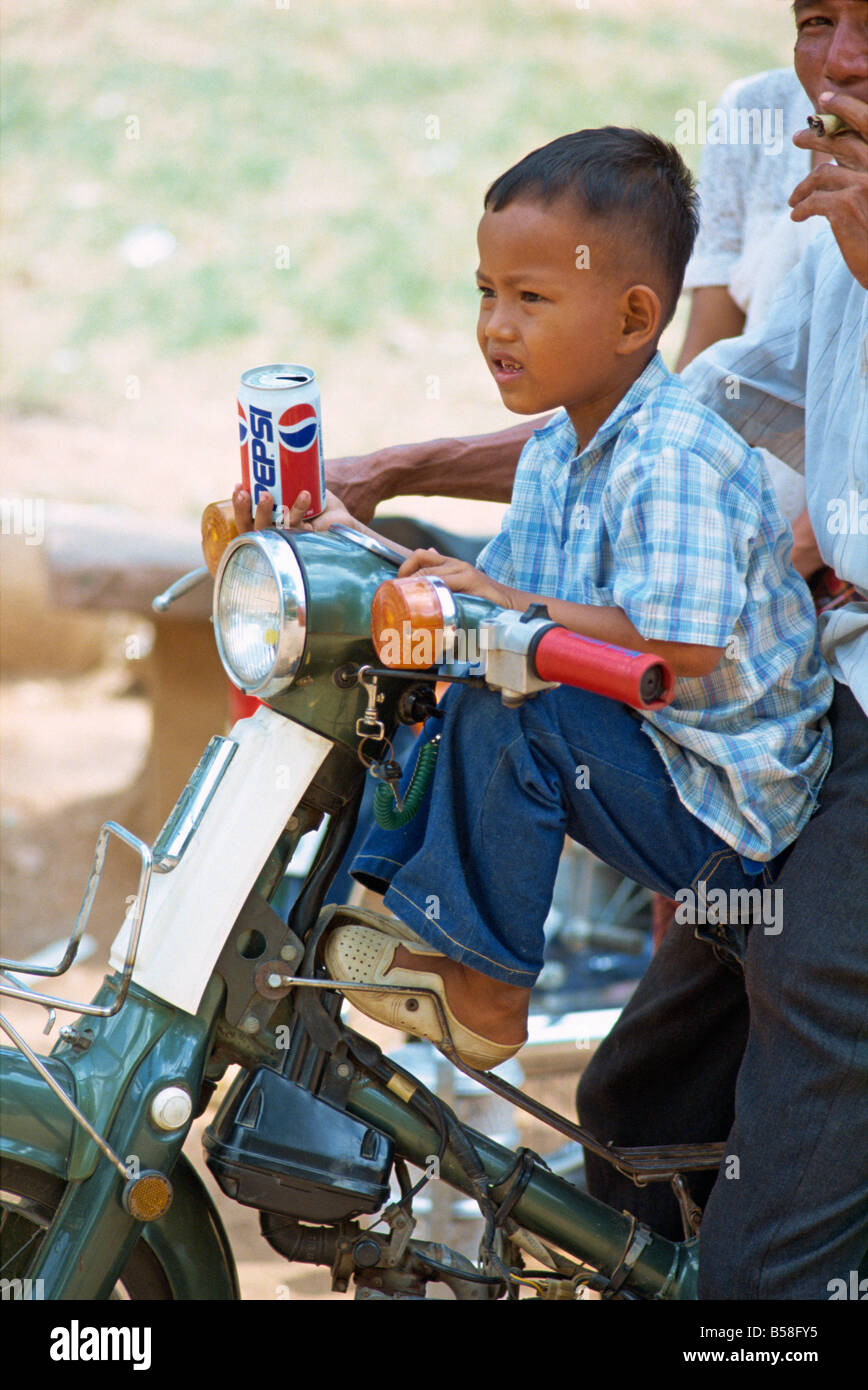 Portrait of a small boy holding a can of Pepsi on a motorcycle in Phnom ...