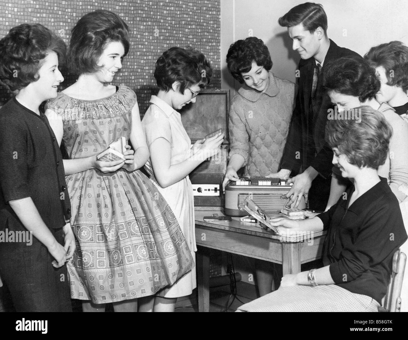 Teenagers crowd around the tape and record player at their local youth ...