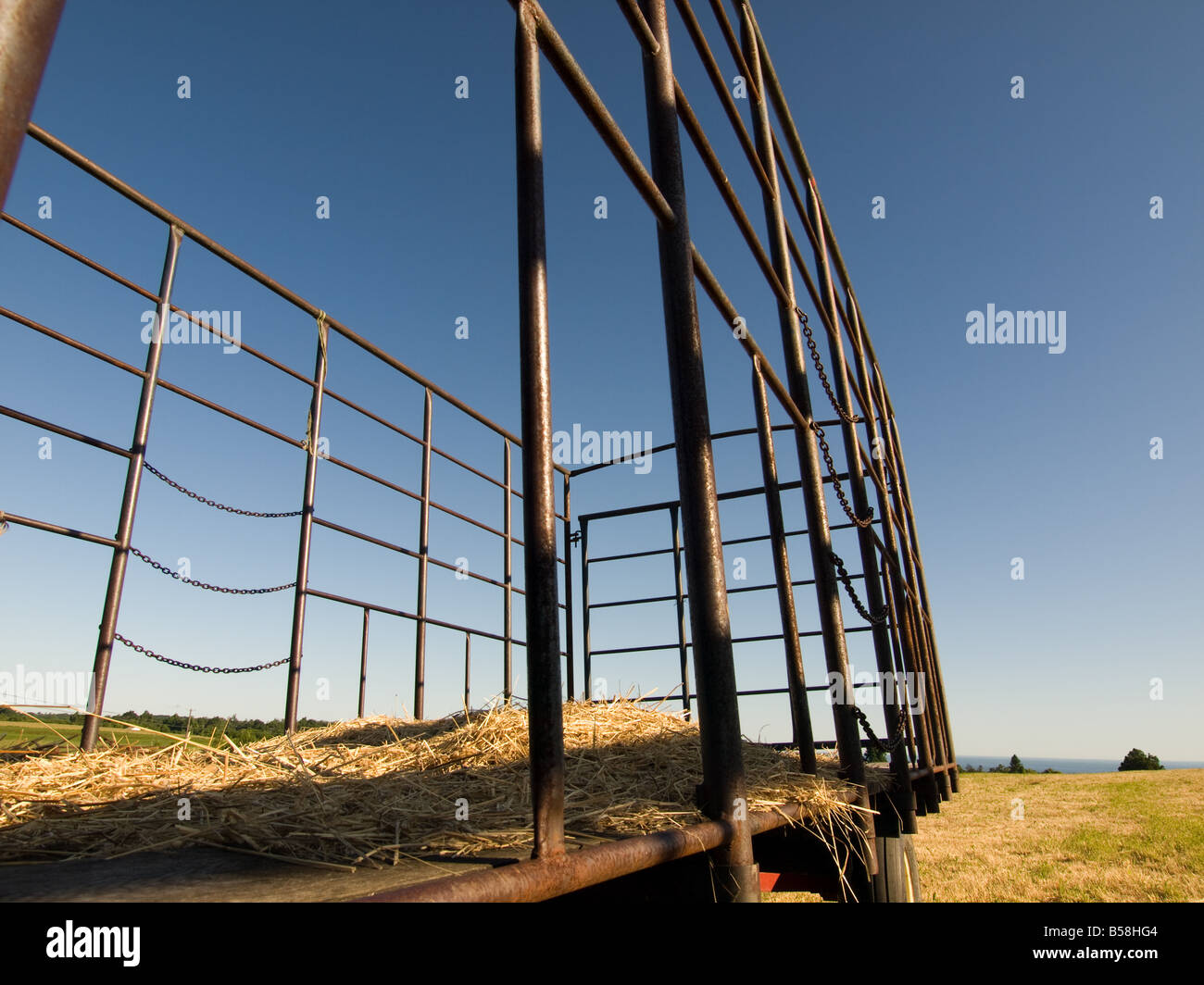An almost empty hay wagon in a farm field under a clear blue sky Stock ...