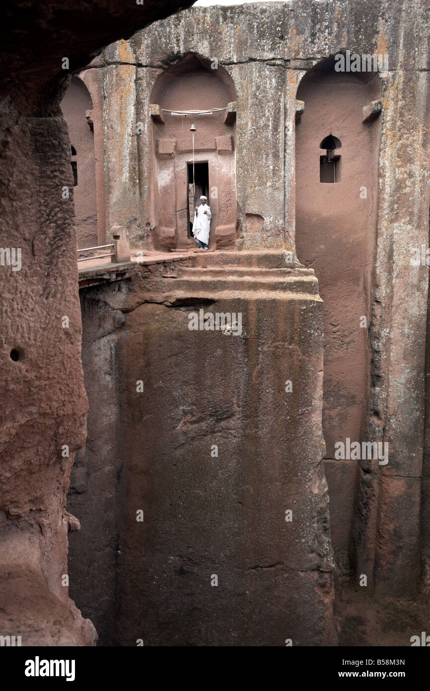 A priest stands at the entrance to the rock-hewn church of Bet Gabriel ...
