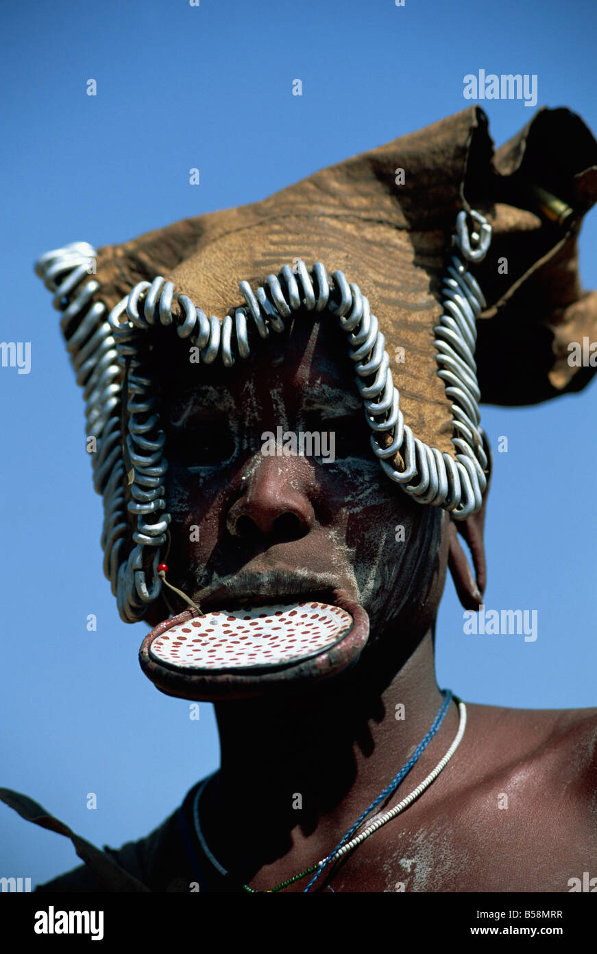 A member of the Mursi tribe with lip plates head dress and body paint ...