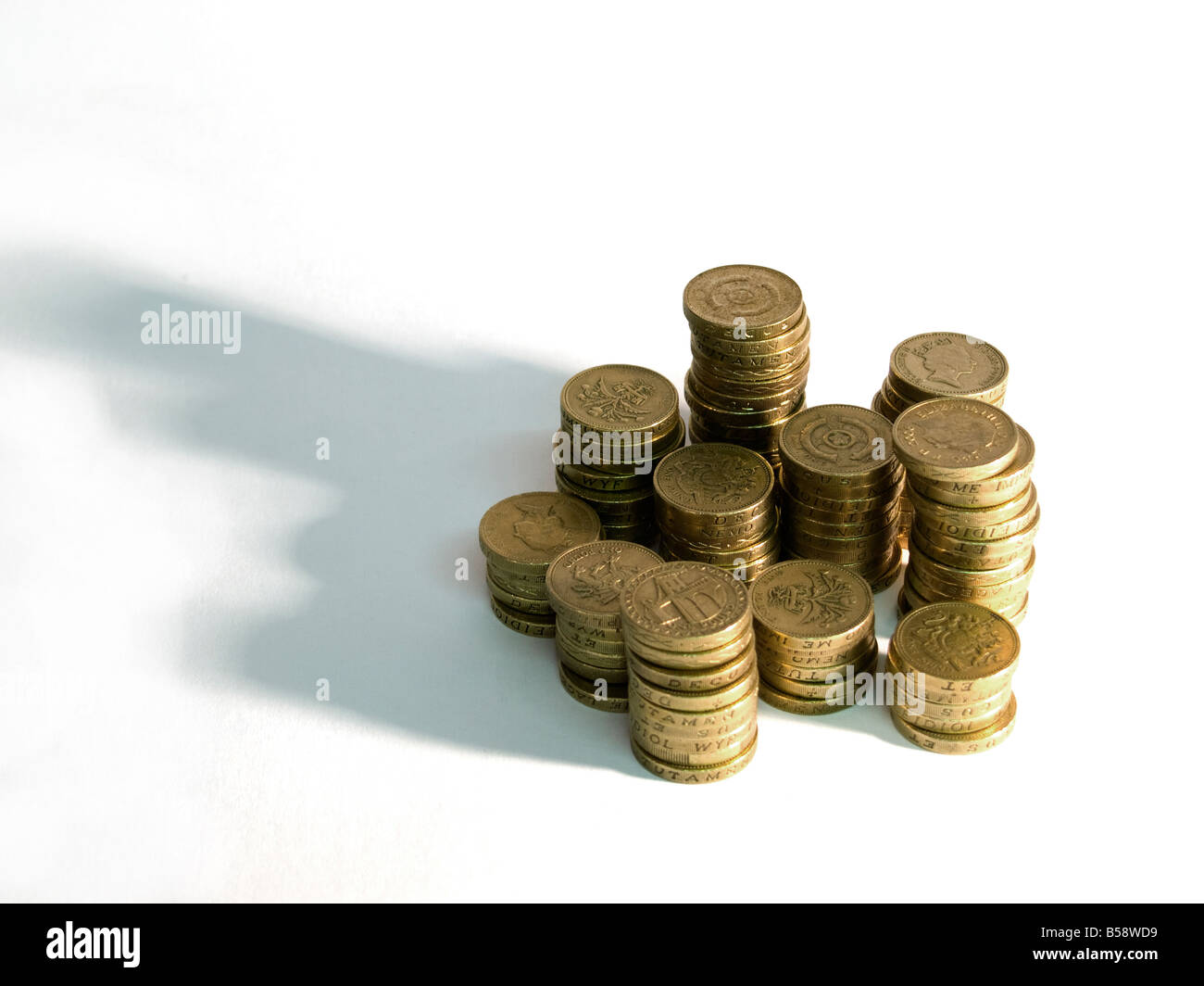 Irregular stack of UK sterling one pound coins casting a shadow on ...