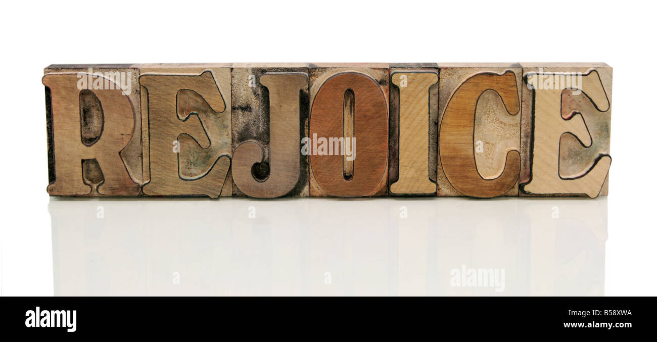 the word 'rejoice' in old wood type isolated on white with a reflection ...