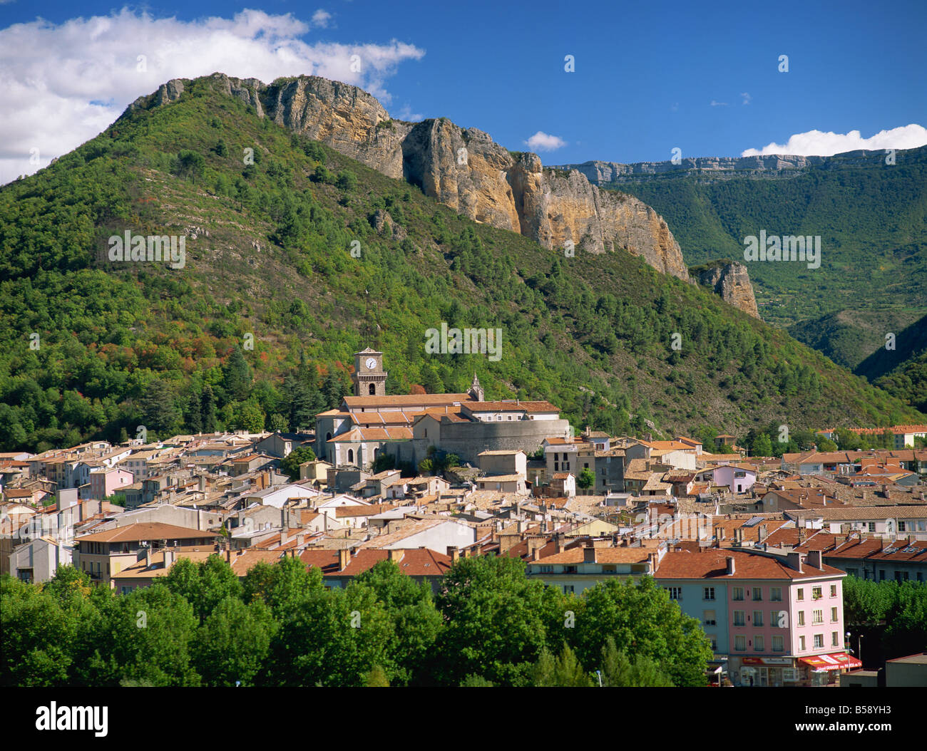 Houses and church with bell tower below a rocky hill at Digne les Bains ...