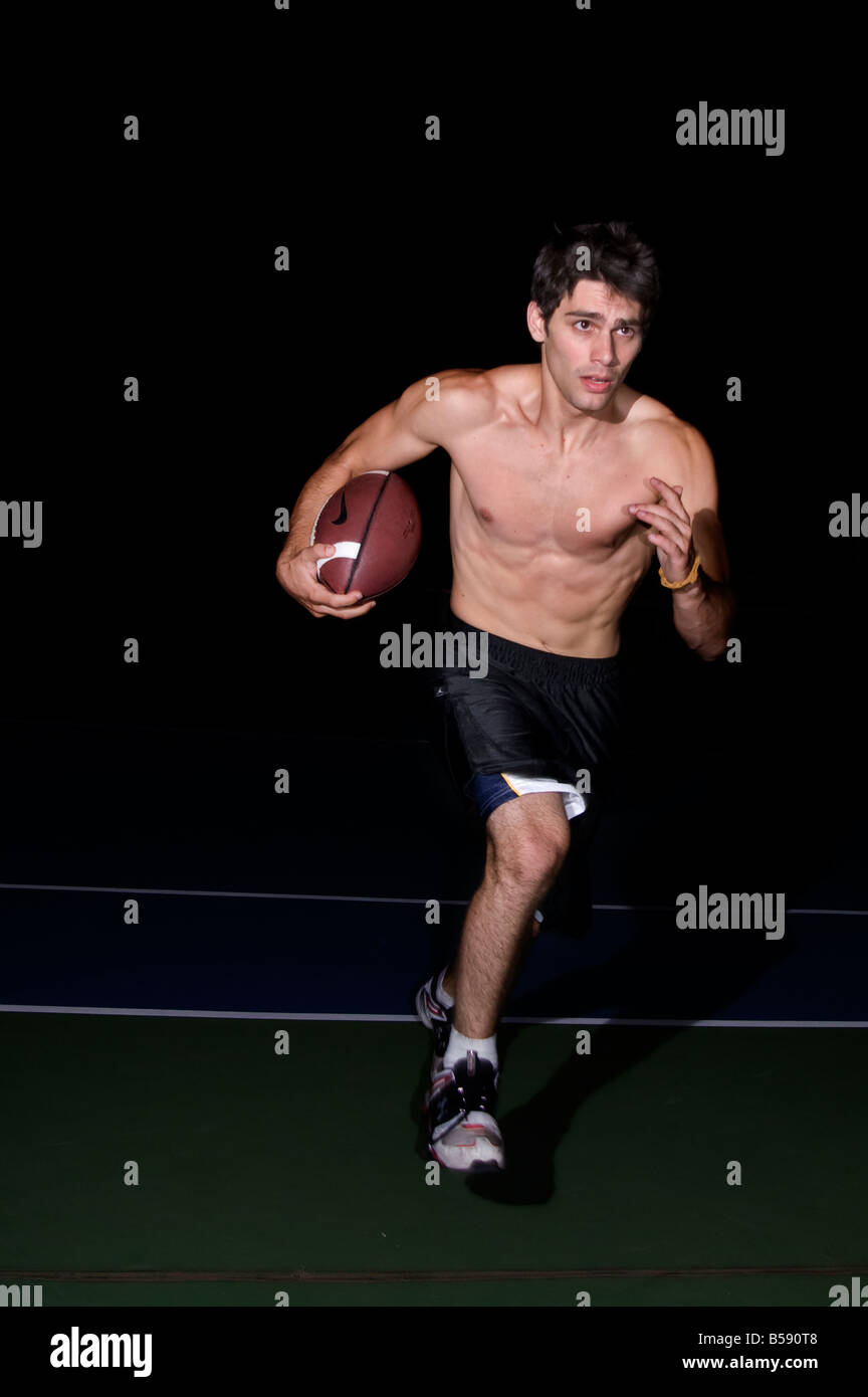 Young man running with a football Stock Photo - Alamy