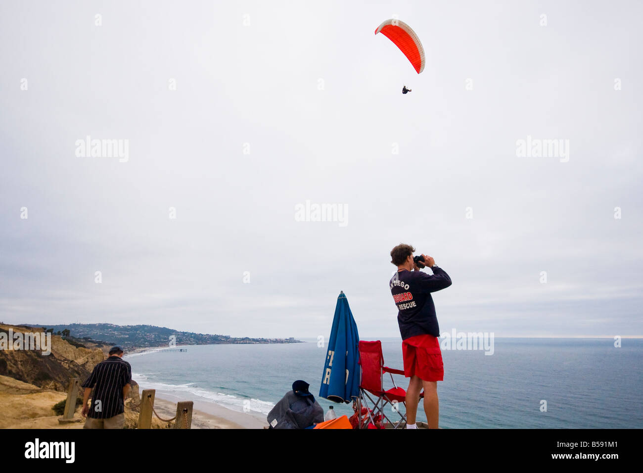 Lifeguard keeping watch of the beach as a paraglider soars through the ...