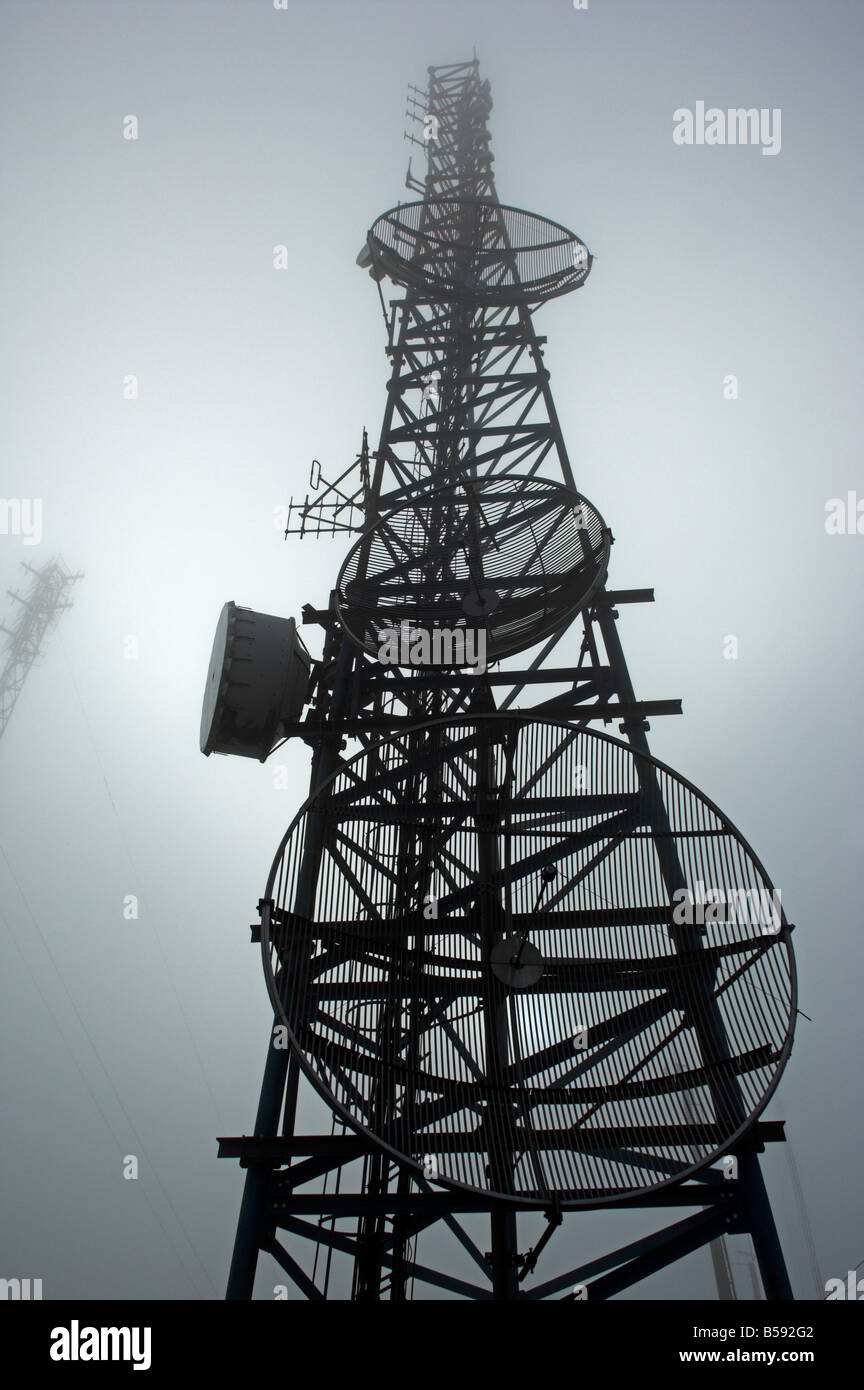 Communications tower with parabolic dish and microwave aerials in fog ...