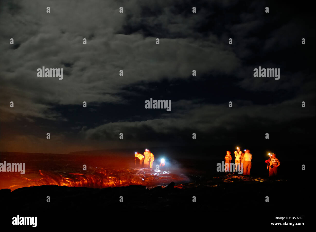 Group of people viewing a lava tube skylight and flowing lava Stock ...