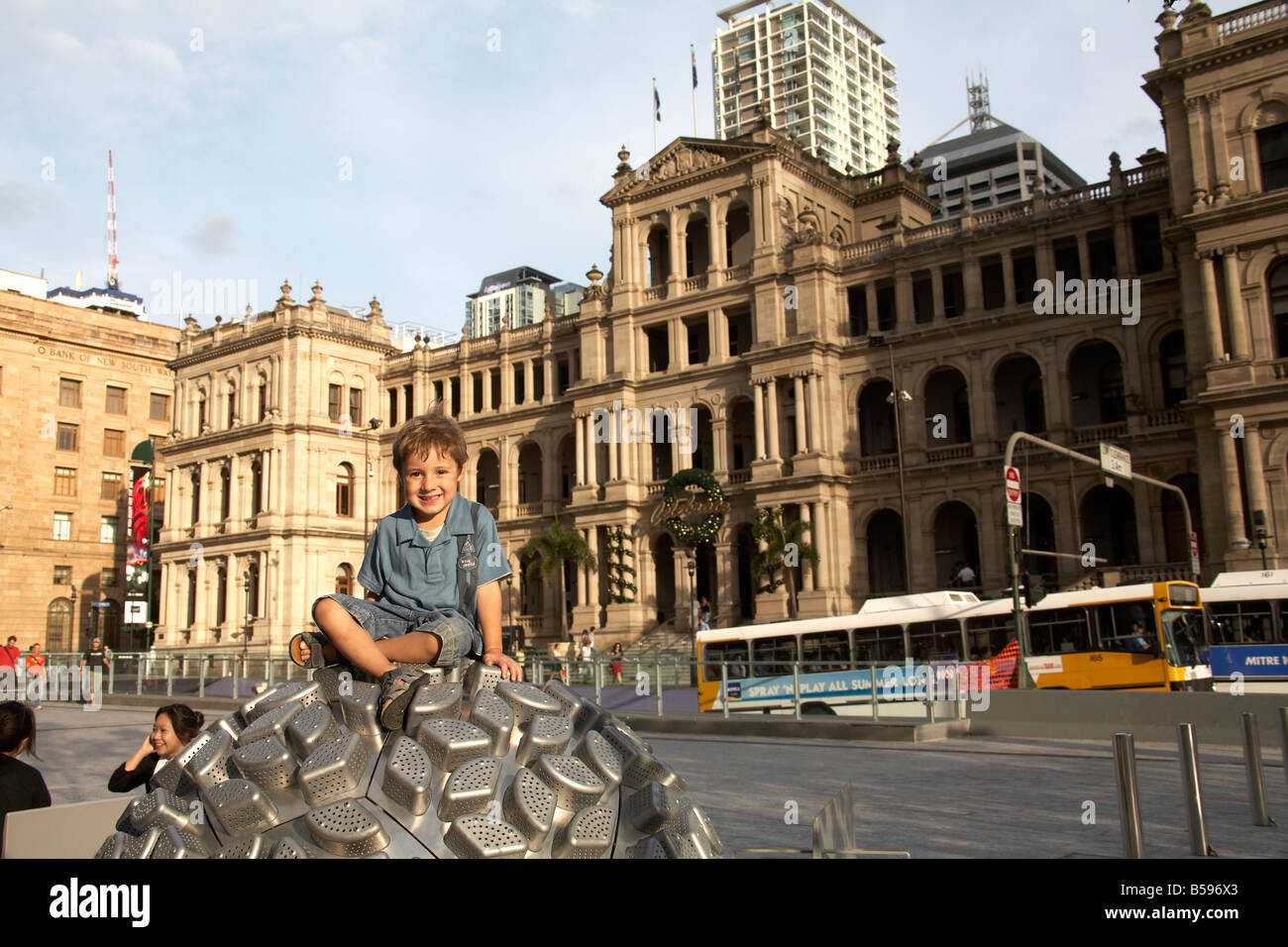 Young boy child sitting on sculpture outside Brisbane Square new modern ...