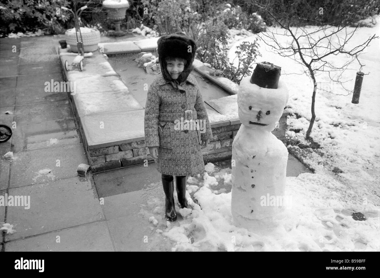A girl with the snowman she built during the last fall of snow. March ...