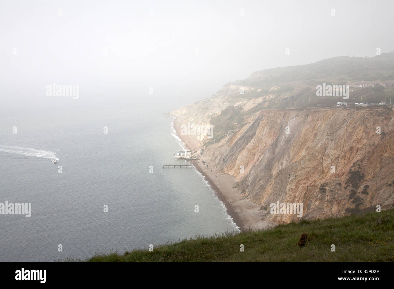 Alum Bay and coloured sands cliffs above the sea in thick mist cloud ...
