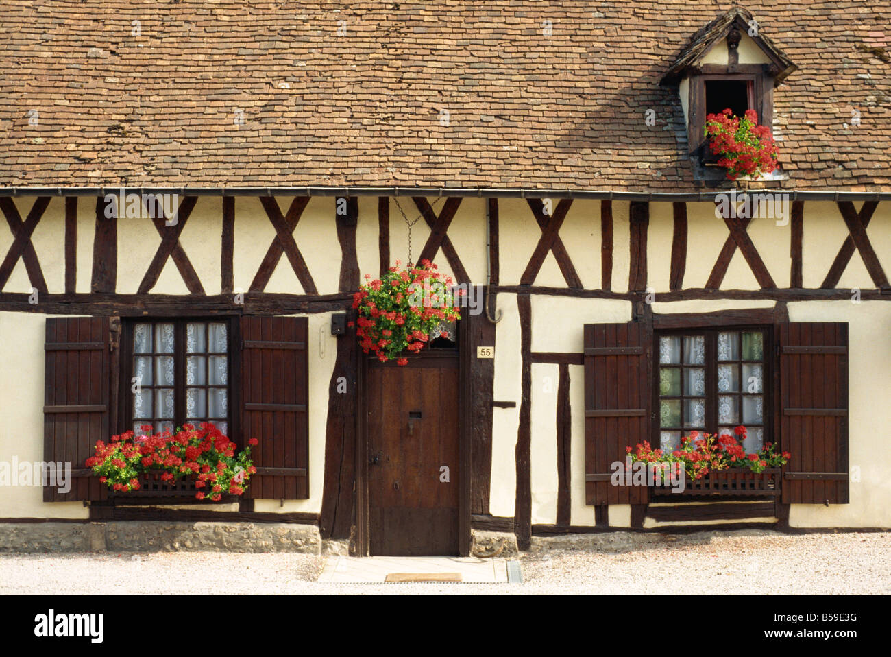 Typical timbered French cottage with geraniums in window boxes and ...