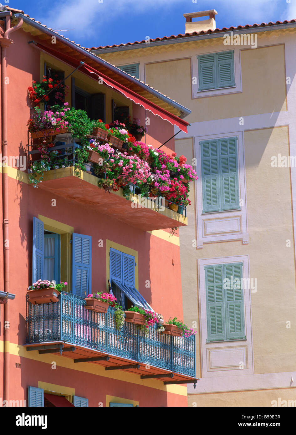 Balconies with blue wrought iron and shutters, pots of geraniums ...