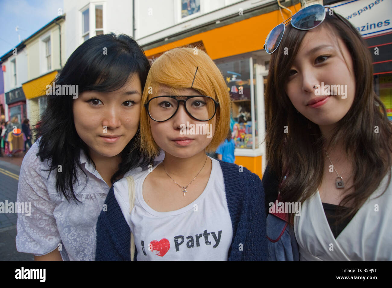 Three Young Japanese Girl Friends Standing Looking Into Camera On