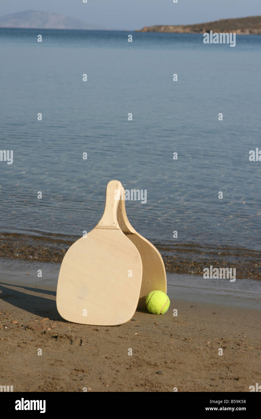two wooden beach rackets by the shore with yellow ball Stock Photo - Alamy