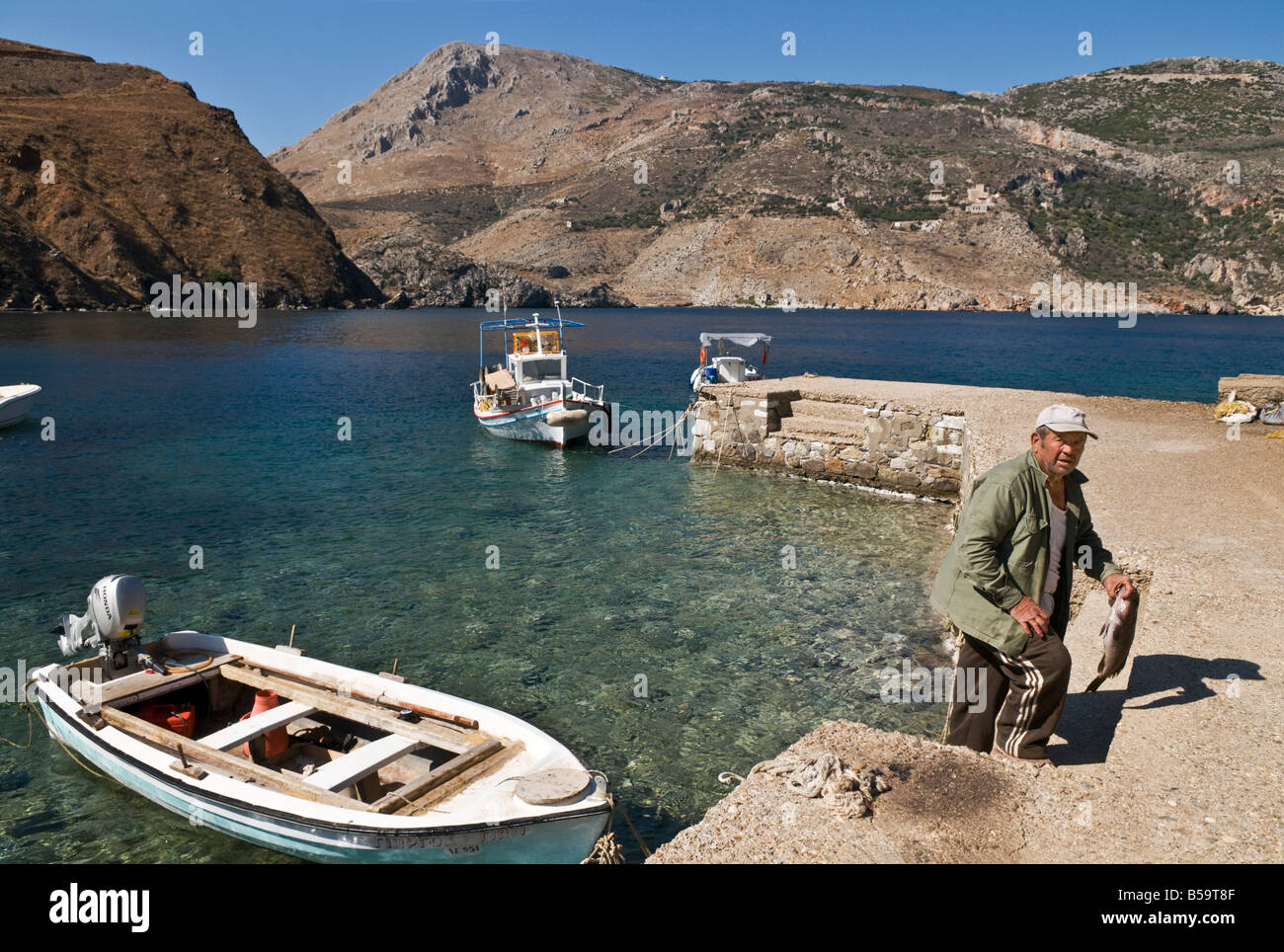 A fisherman with his catch in the harbour of Porto Kagio in the deep ...