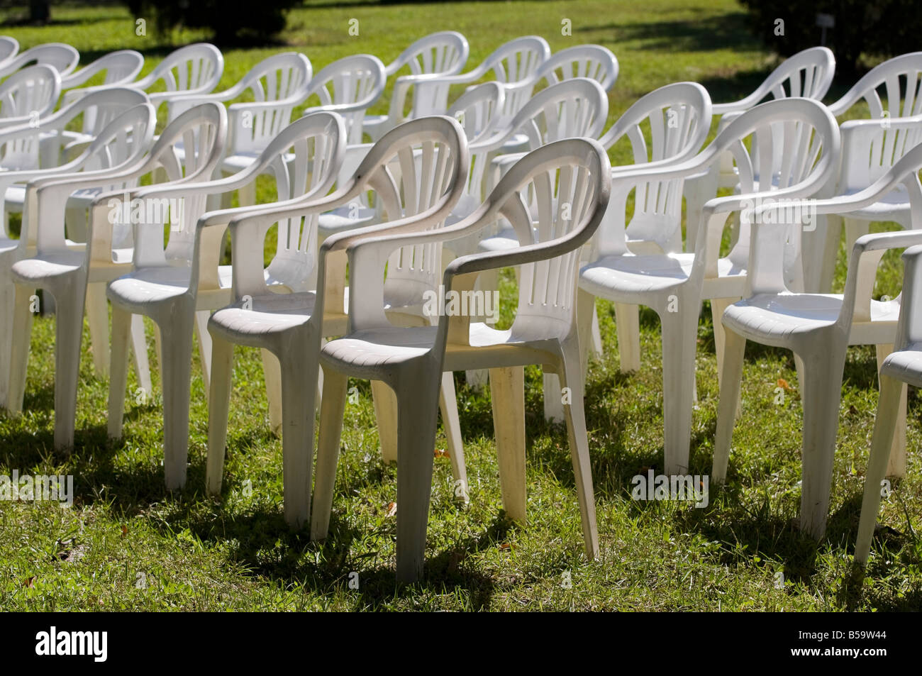 line up of white chairs in garden setting Stock Photo - Alamy