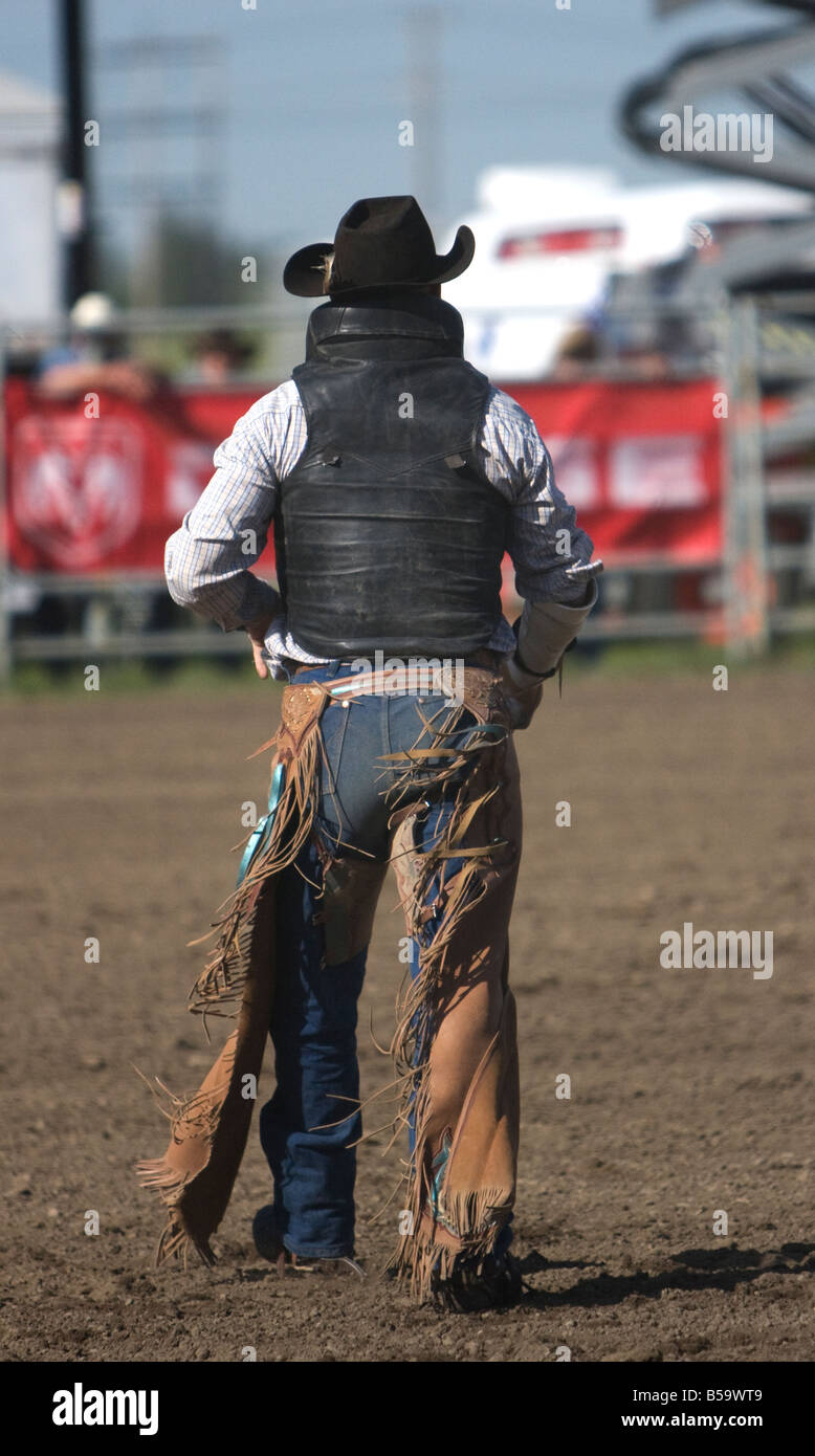 A rear profile of a cowboy walking across the sand at a rodeo Stock ...