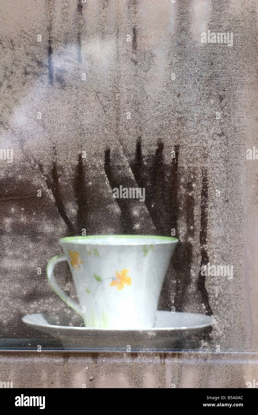 Teacup and saucer seen through old dusty window Stock Photo - Alamy