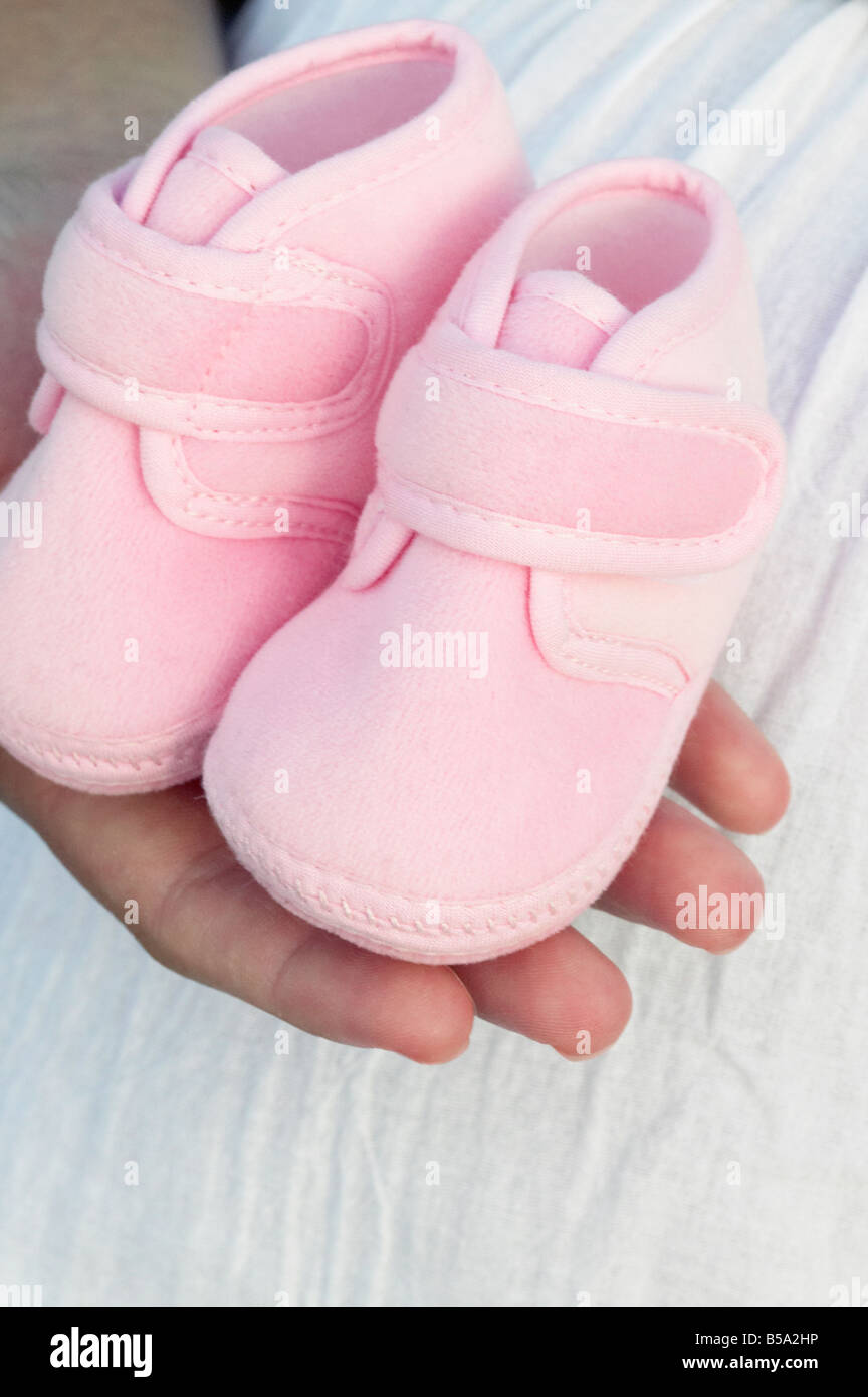 Mother's hand holding infants shoes Stock Photo - Alamy