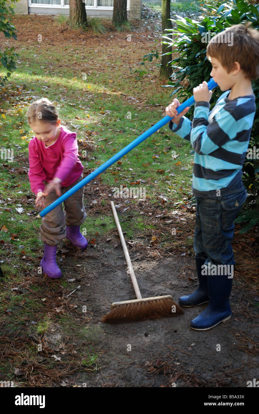 two children playing in garden with broom and stick Stock Photo - Alamy
