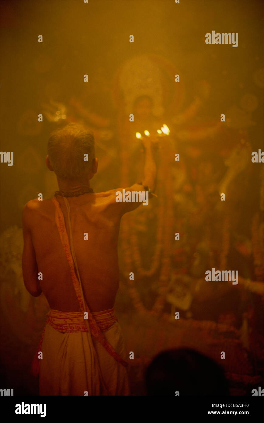 Temple priest before the image of the ten armed warrior goddess Durga ...