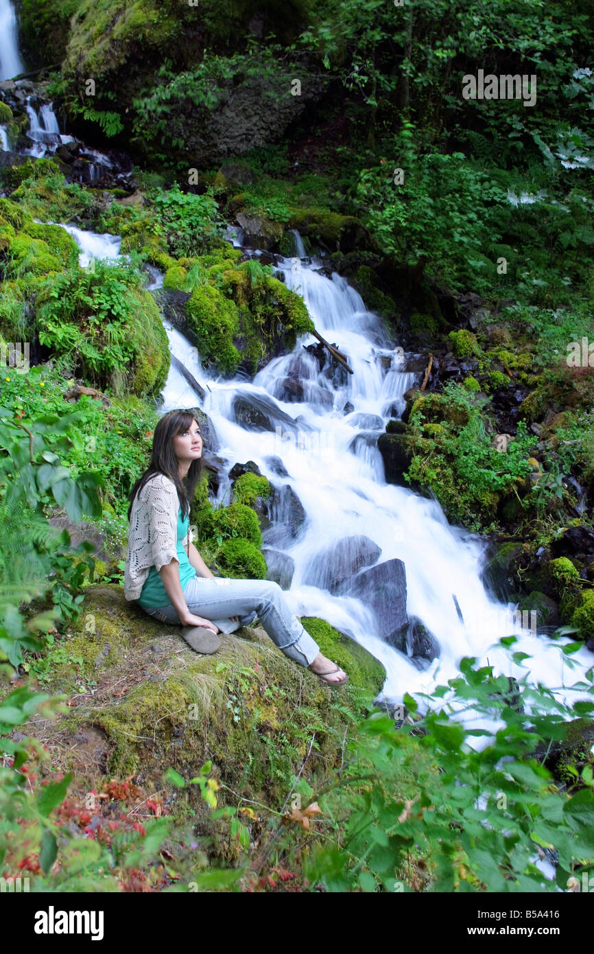 Young girl sitting by a waterfall Stock Photo - Alamy