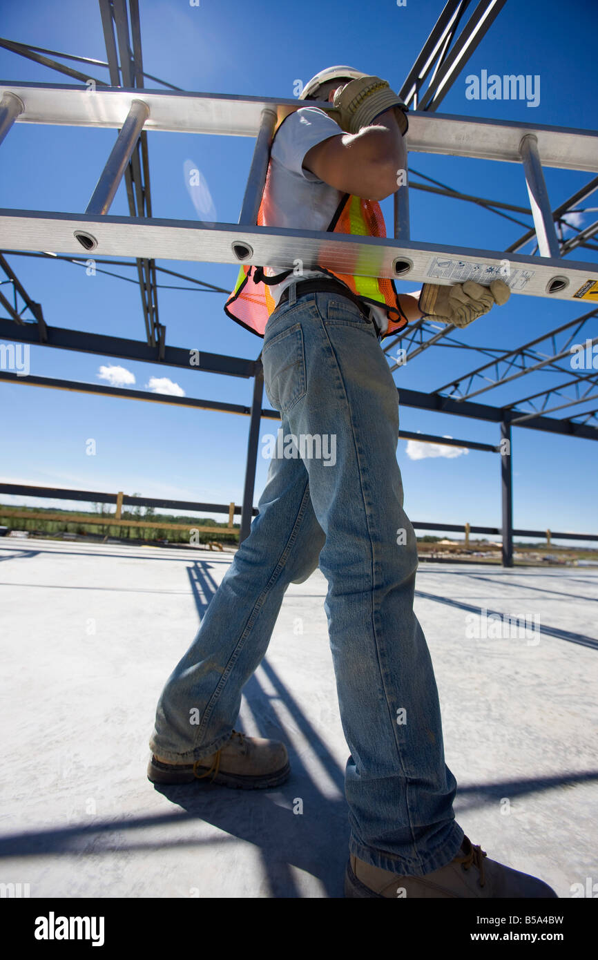 Construction worker carrying a ladder Stock Photo - Alamy