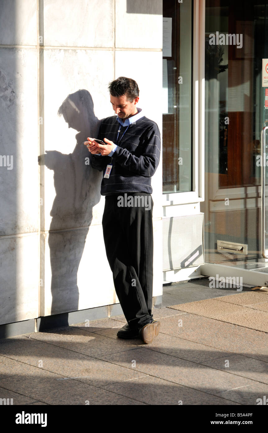 Smoking young man with mobile phone organiser Stock Photo - Alamy