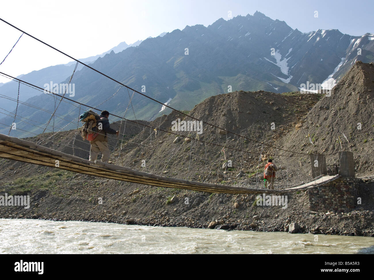 Two men carrying backpacks crossing a wooden suspended bridge, Mud, Pin ...