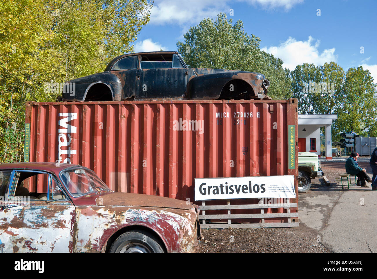 An old junk car sits on top of a shipping container, Autofriedhof ...