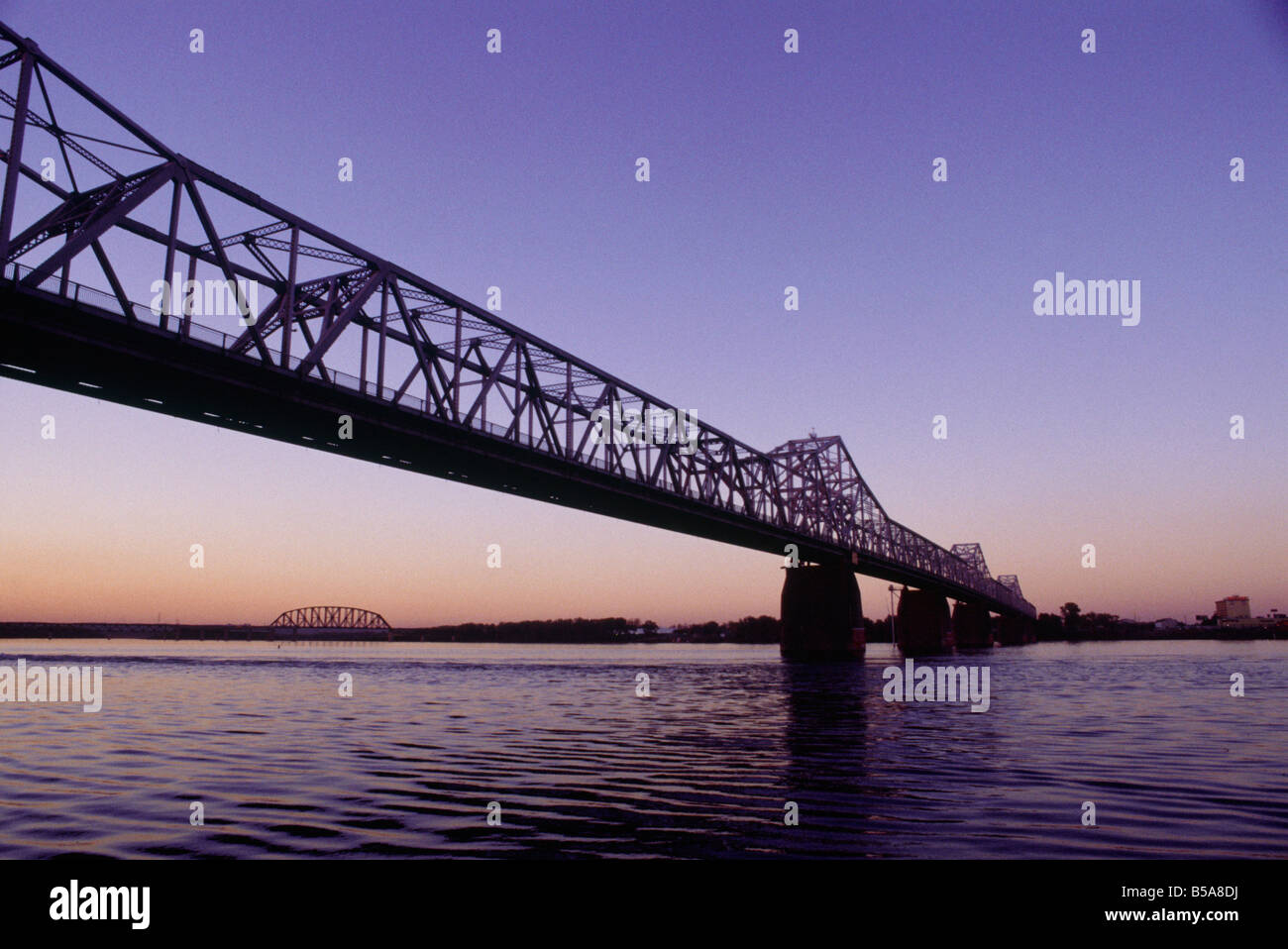 Steel structure bridge Across wide expanse of water Dusk Purple pink ...