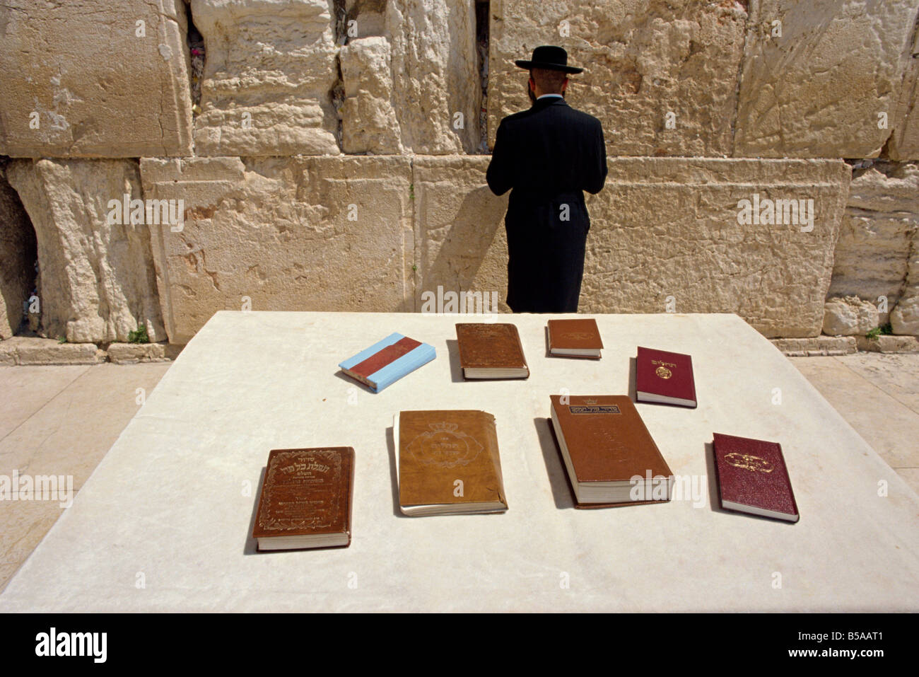 Religious books on table and Jewish man facing the Western Wall ...